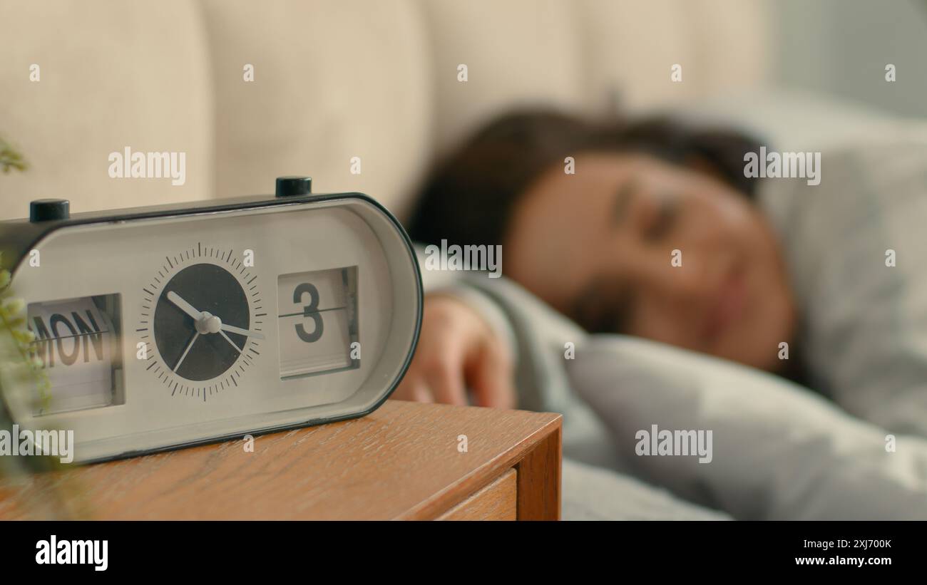 Young Caucasian woman lying on bed smiling turning off alarm clock good ...
