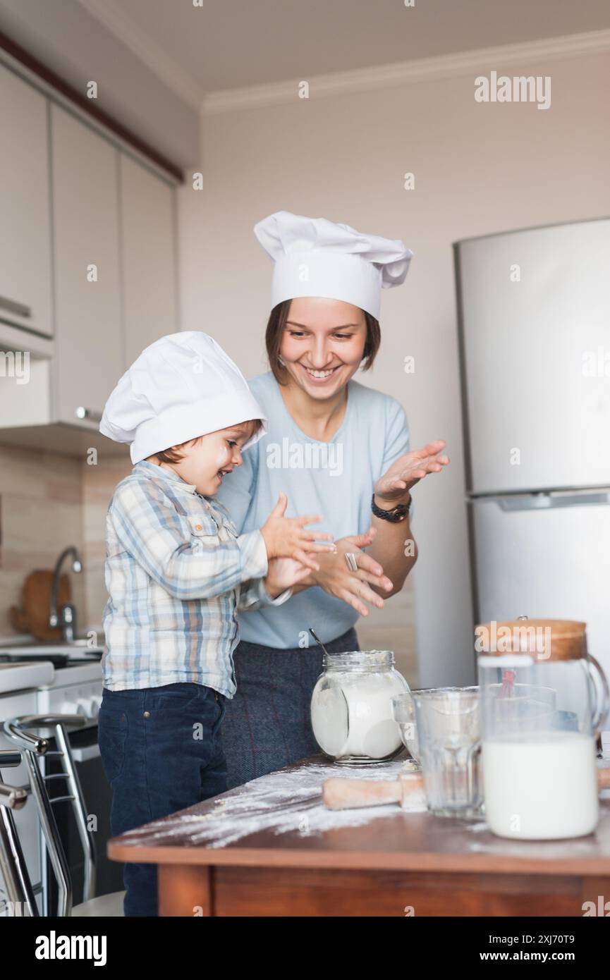 mother and child clapping hands while preparing dough at kitchen Stock ...