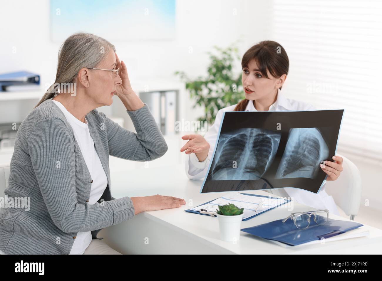 Lung disease. Doctor with chest x-ray consulting patient in clinic ...