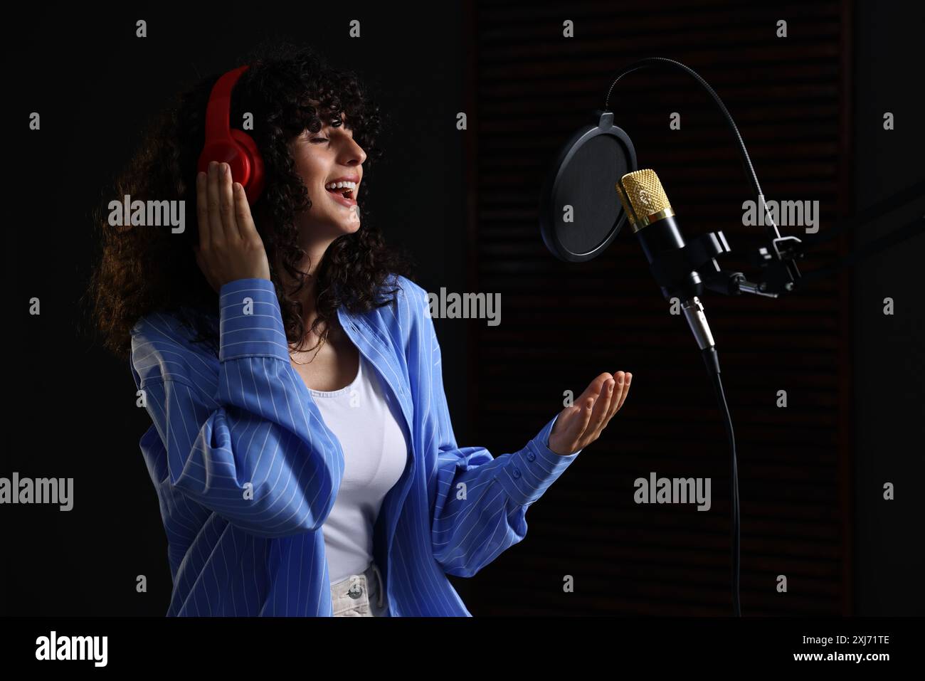 Vocalist with headphones singing into microphone in professional record ...