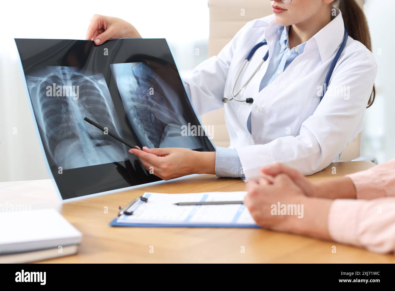 Lung disease. Doctor showing chest x-ray to her patient at table in ...