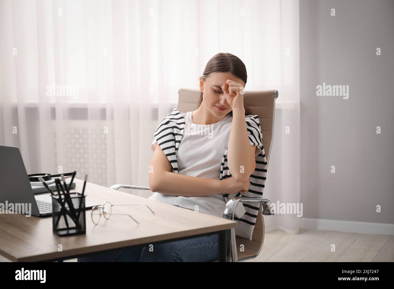 Embarrassed woman at wooden table with laptop in office Stock Photo - Alamy