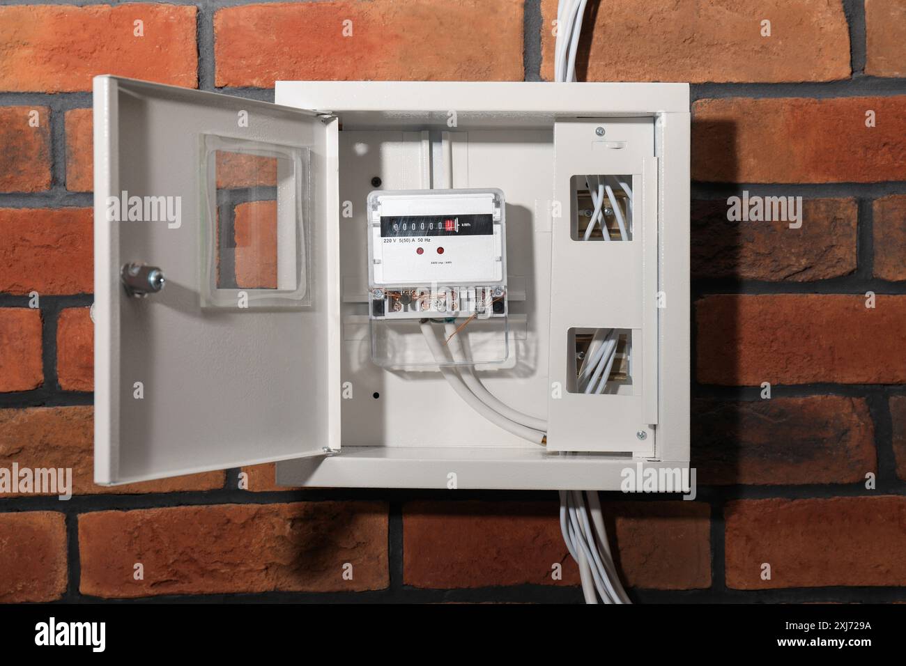 Electric meter in fuse box on red brick wall. Energy measuring device ...