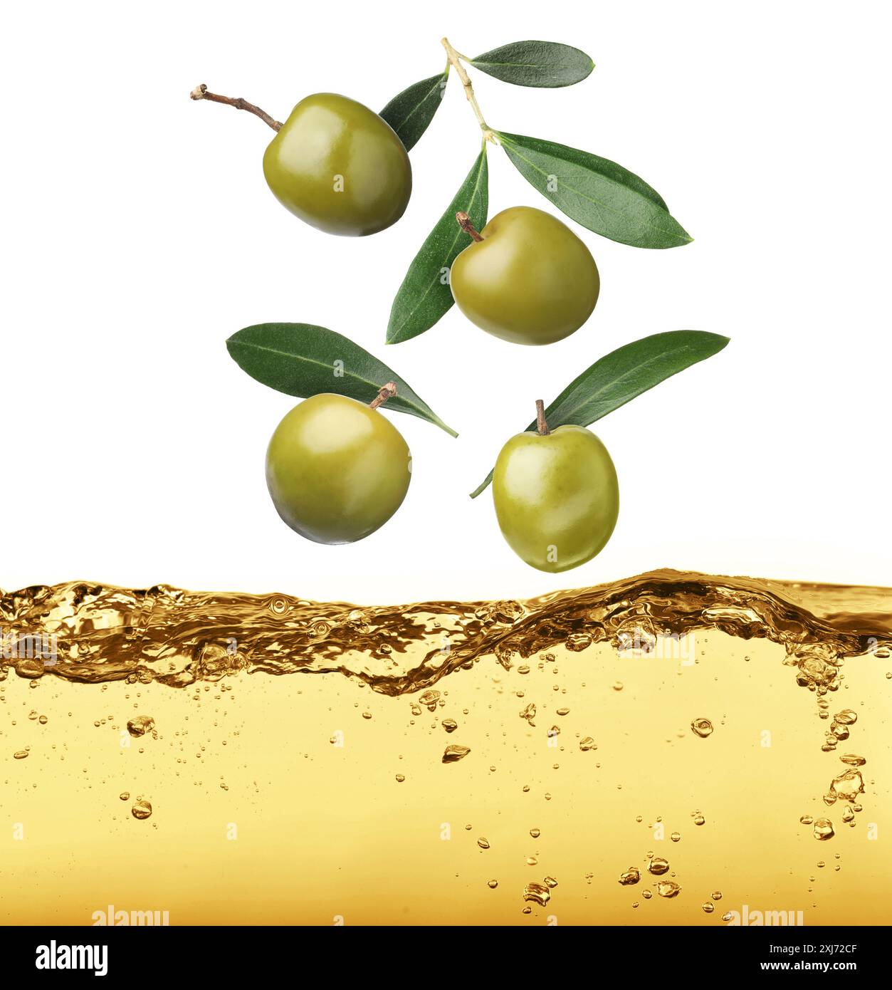 Green olives and leaves falling into cooking oil on white background ...