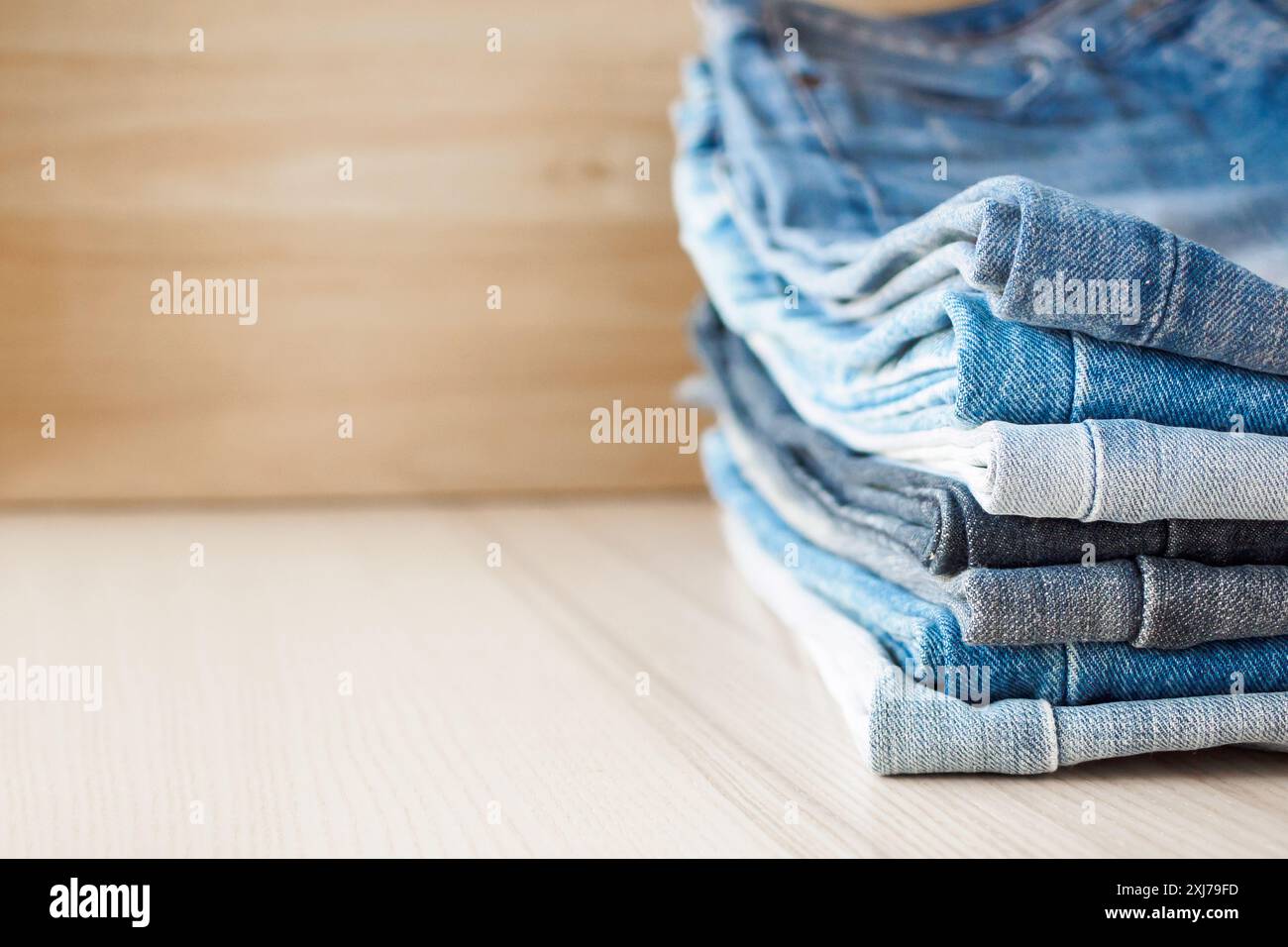 denim blue jeans stack on wood table background Stock Photo - Alamy