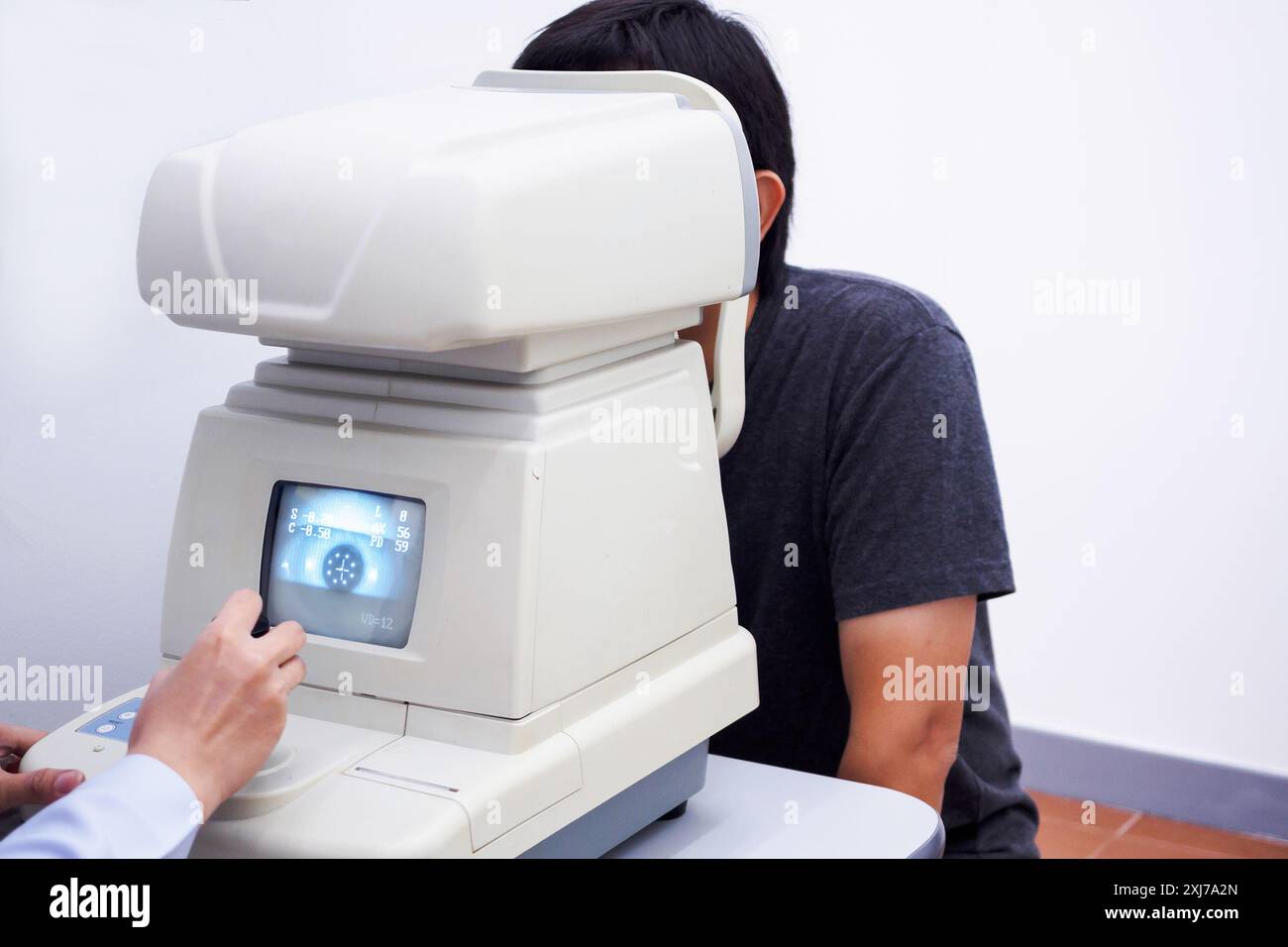 Young handsome asian man take eye exam with optical eye test machine ...