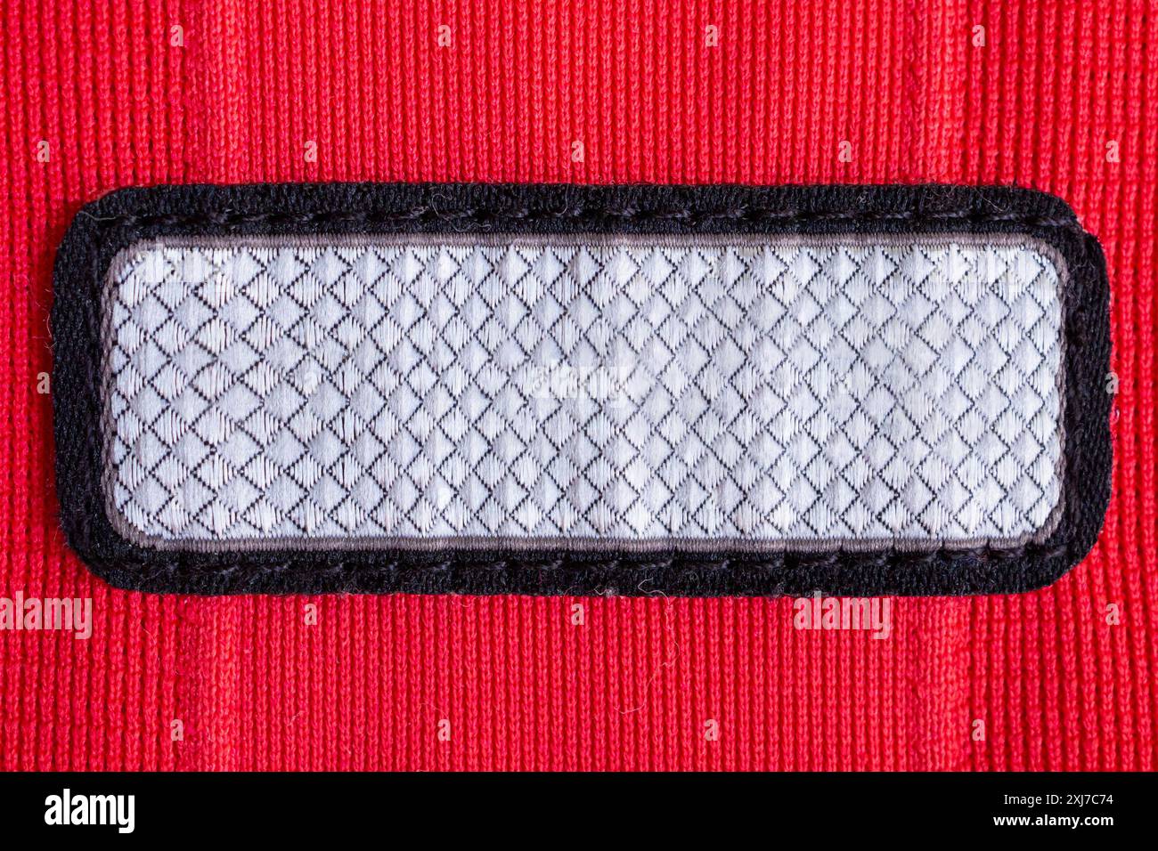 blank clothes tag label on red polyester sport jersey shirt texture ...