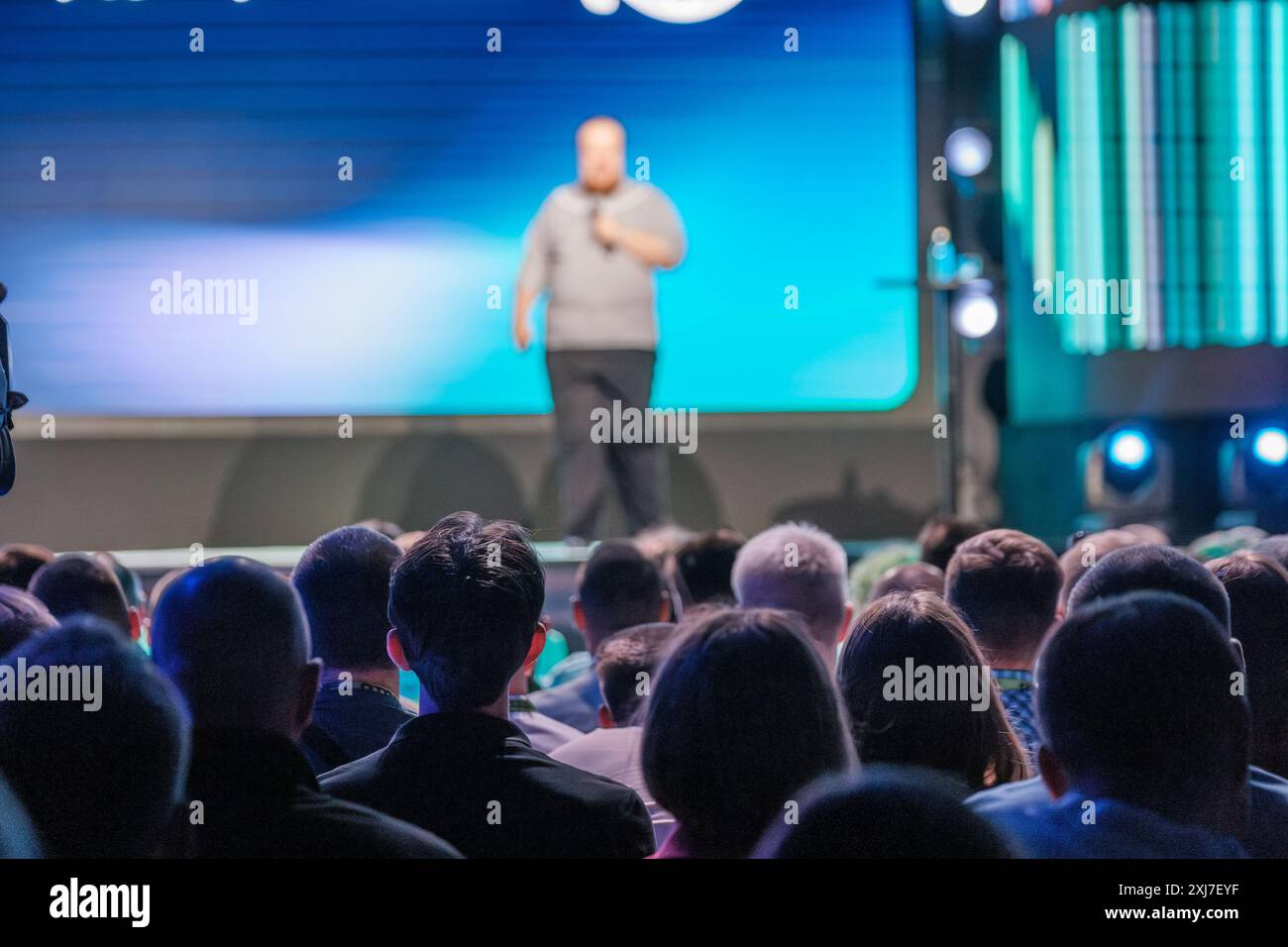 Speaker presenting to a large audience at a business conference with a ...