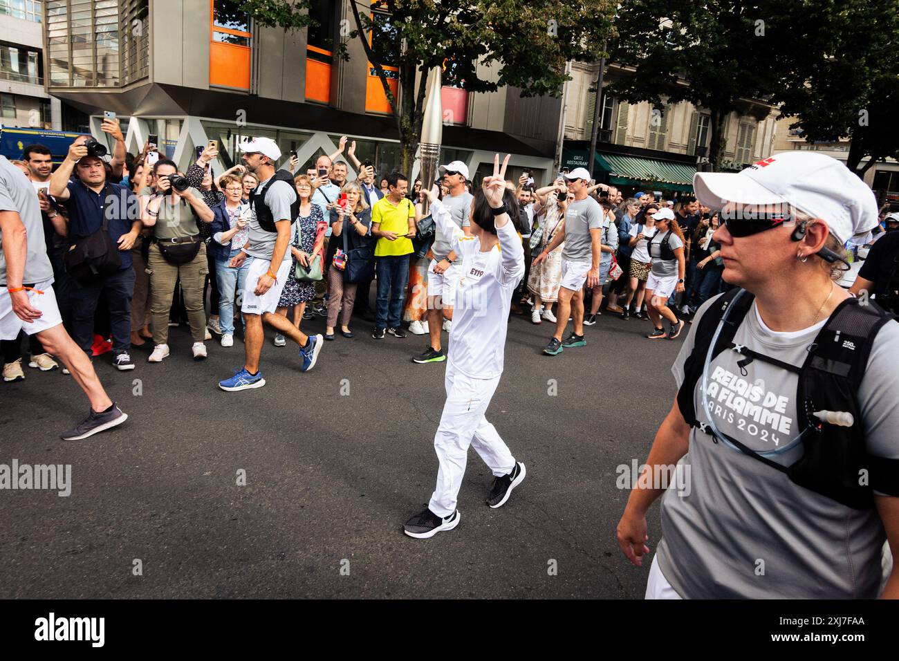 Paris, France. 15th July, 2024. An Olympic torchbearer passes near the ...