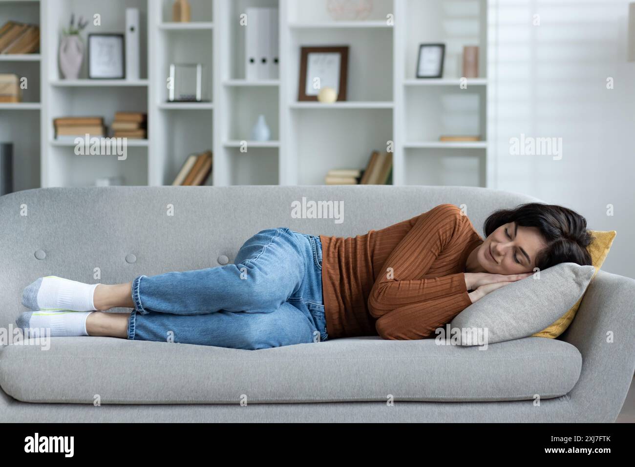 Young woman resting at home, lying on sofa and sleeping relaxed ...