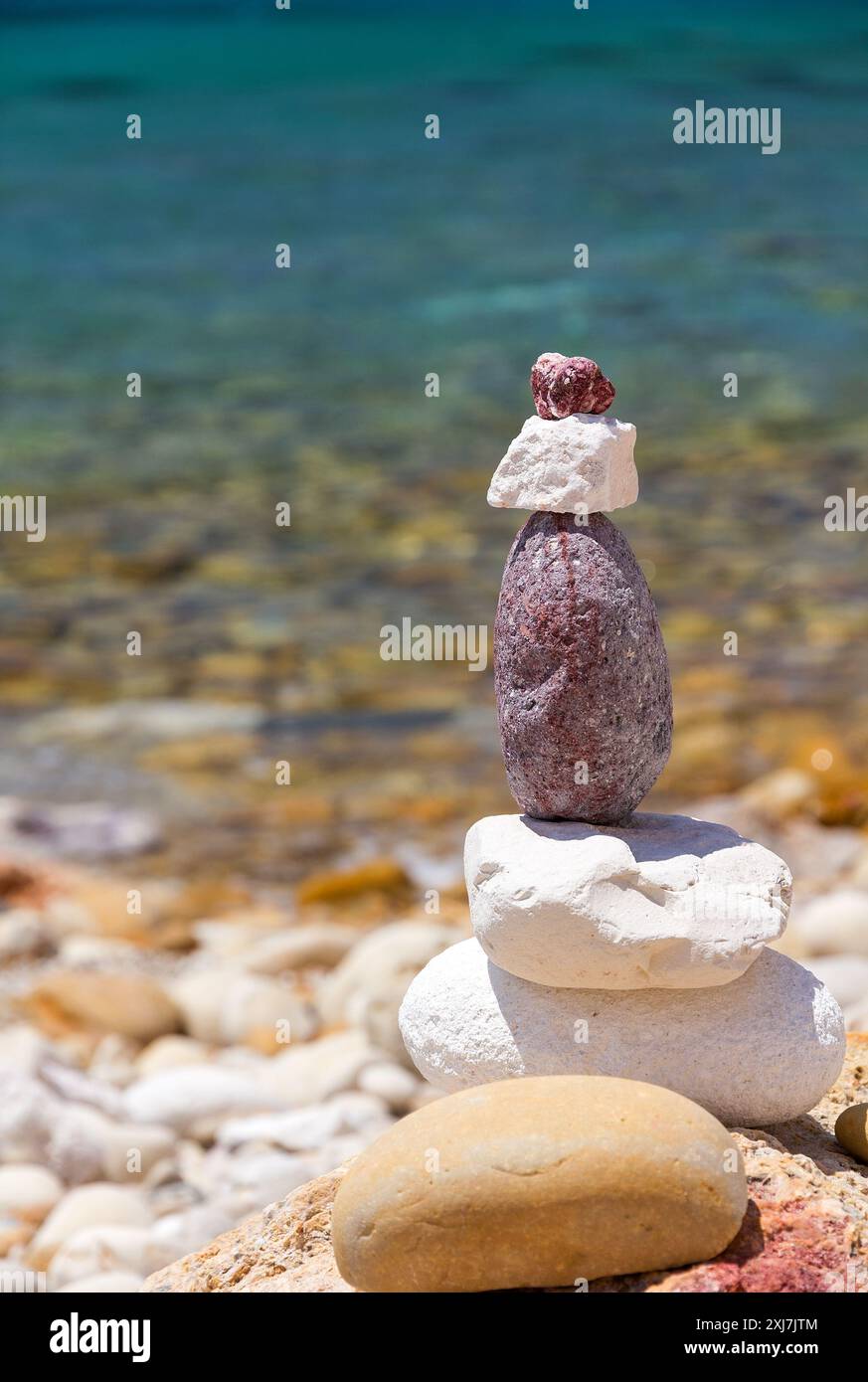 Stack of stones at the beach with emerald sea background Stock Photo ...