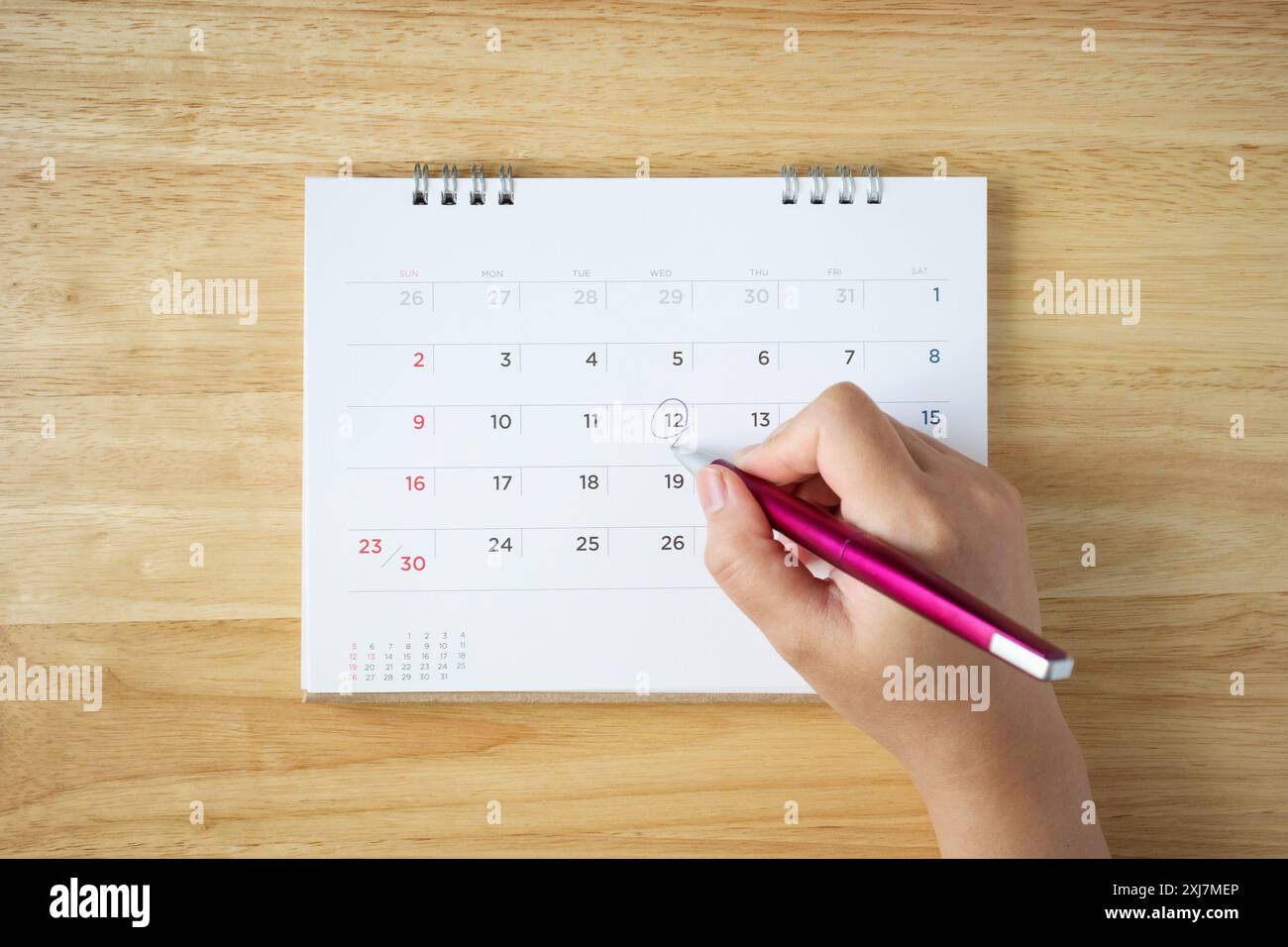 calendar page on table with female hand holding pen, top view Stock ...