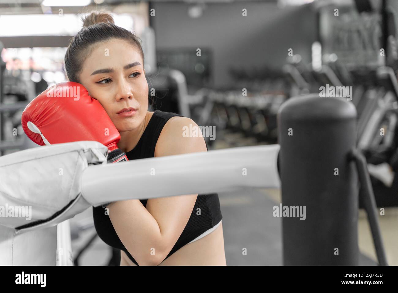 Portrait of a beautiful female boxer resting at the boxing ring in a ...