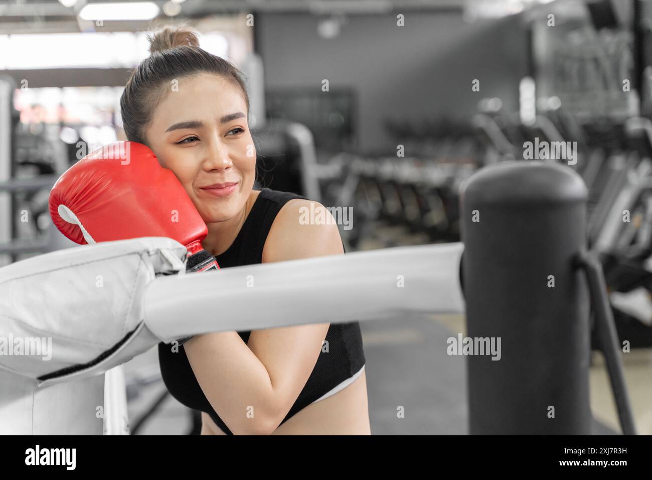 Portrait of a beautiful female boxer resting at the boxing ring in a ...
