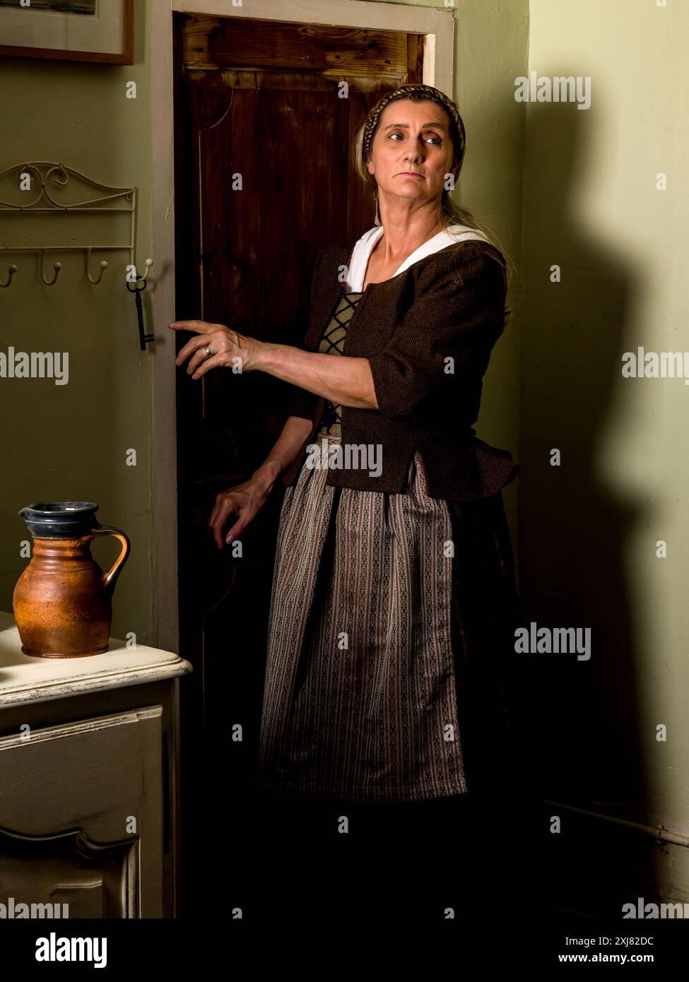 Lady in medieval peasant costume entering an old kitchen and reaching ...