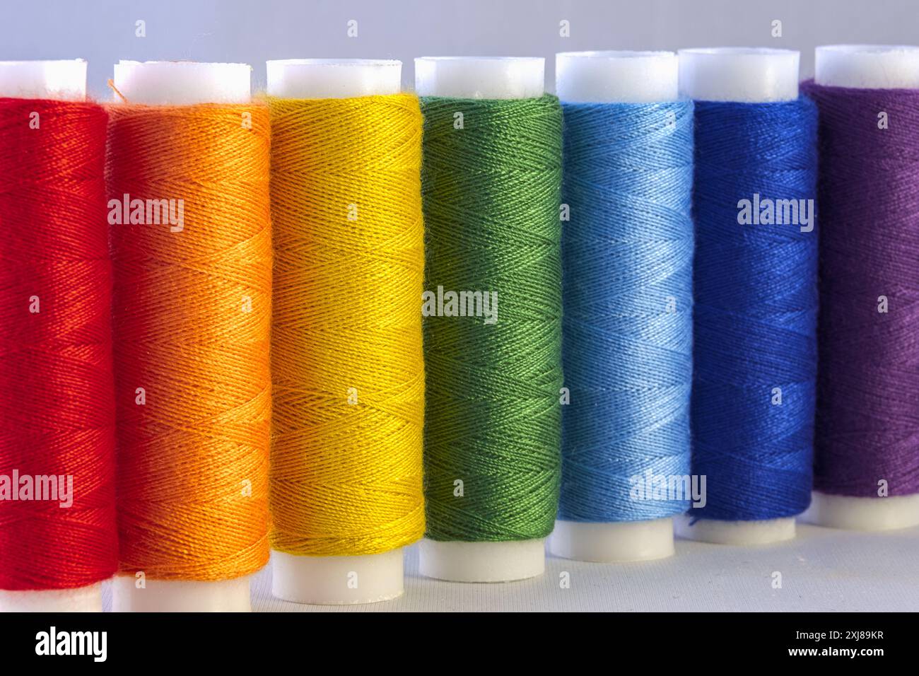 Rainbow colour sewing threads on white background Stock Photo - Alamy
