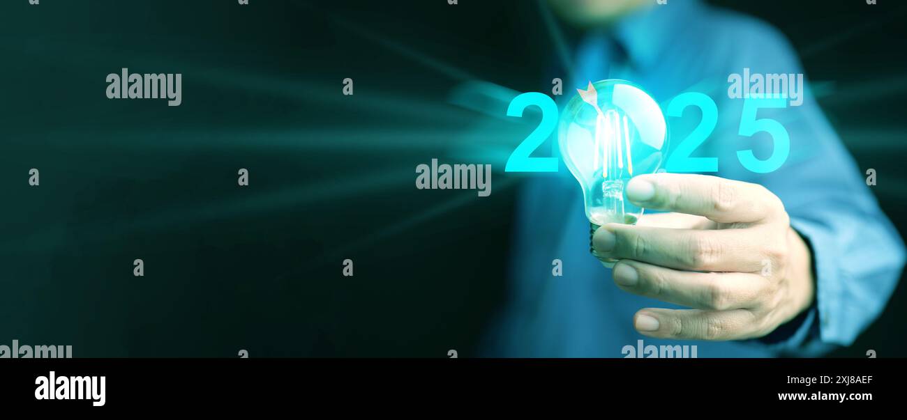 2025 idea and goal. A man holds illuminating lightbulb with virtual ...
