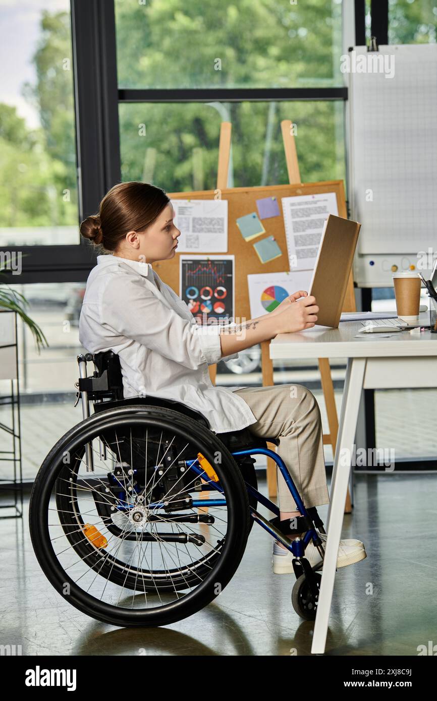 A young businesswoman in a wheelchair works at her desk in a modern ...