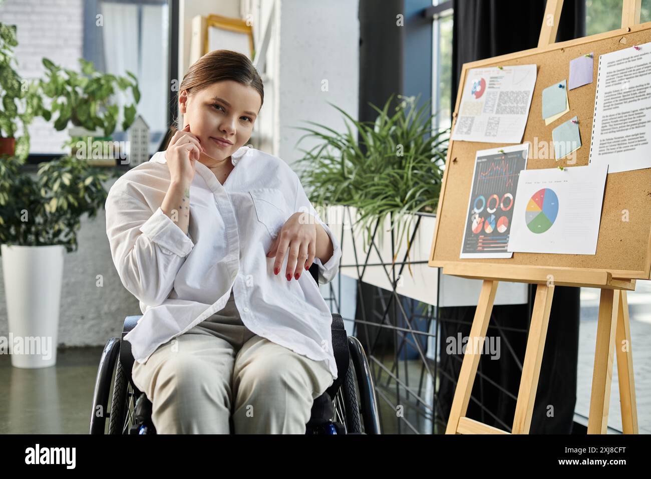 A determined young businesswoman in a wheelchair works at her desk in a ...