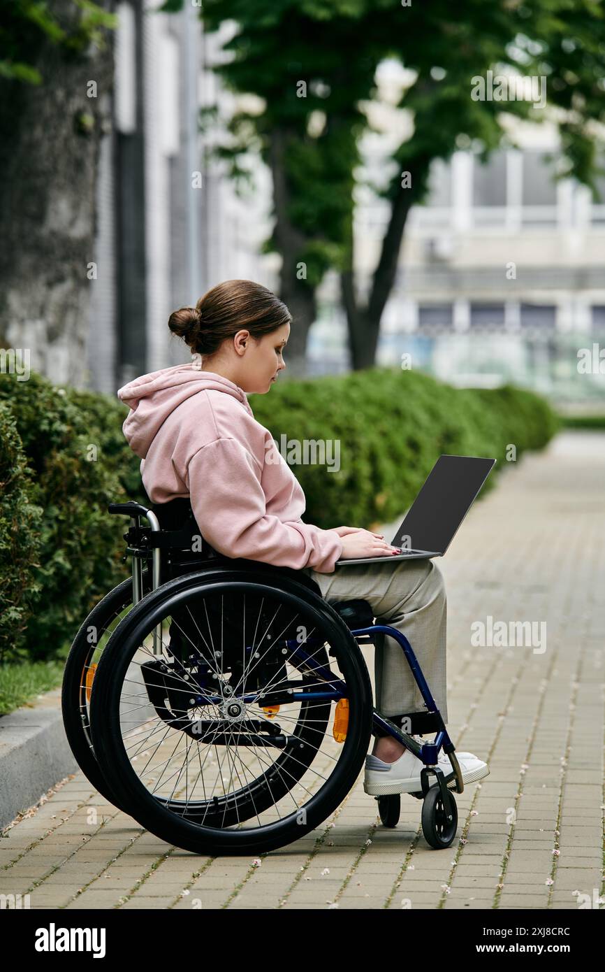 A young woman with a disability sits in a wheelchair on a paved walkway ...