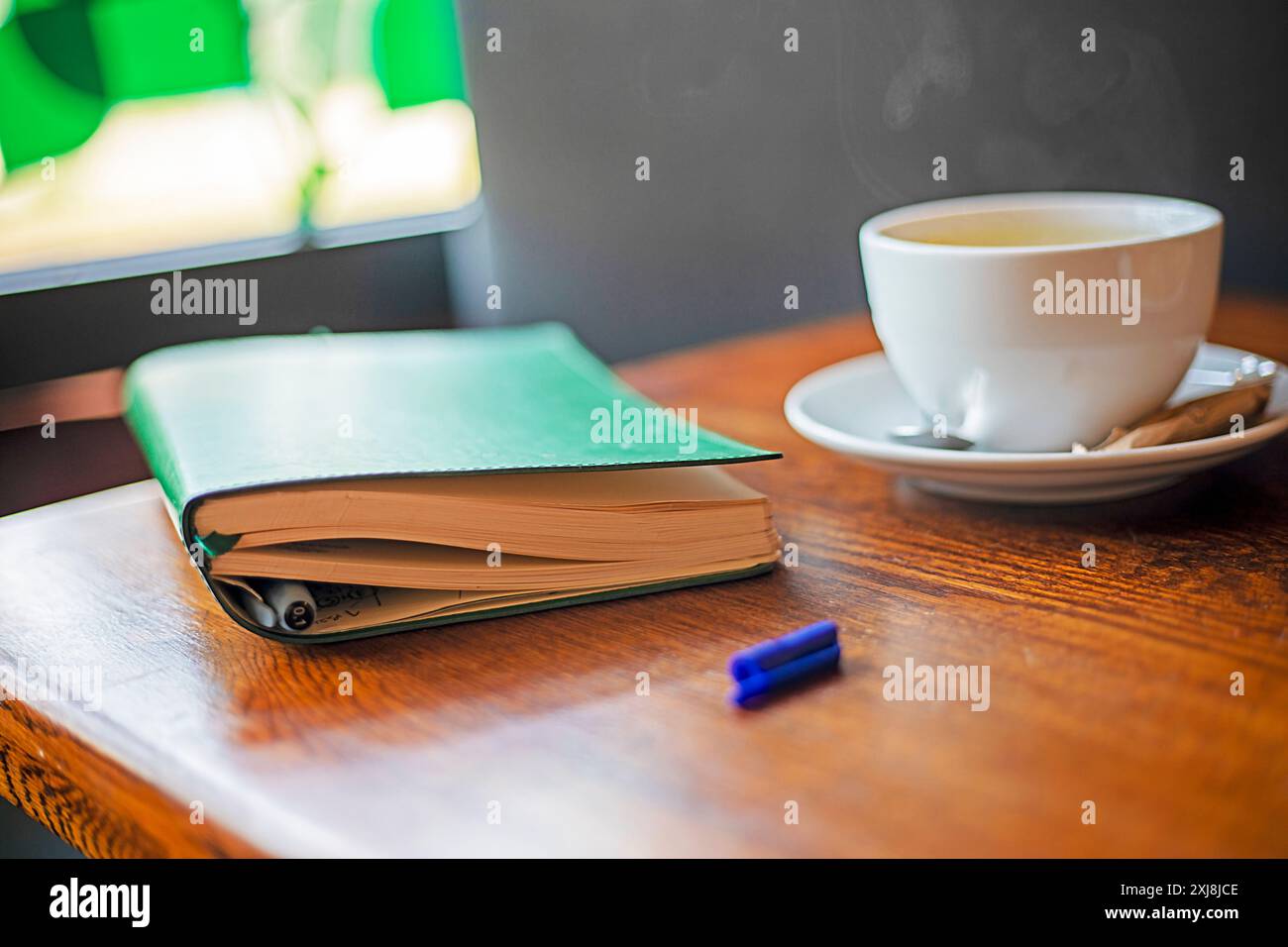 note green weekly planner with a cup of hot coffee or tea on the table ...