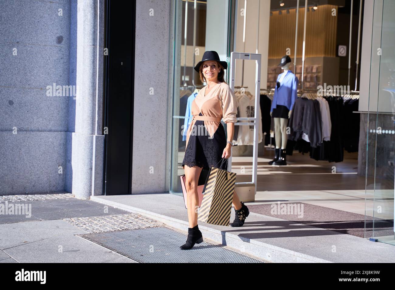 stylish woman leaving a shop with shopping bags in her hand. woman in a ...