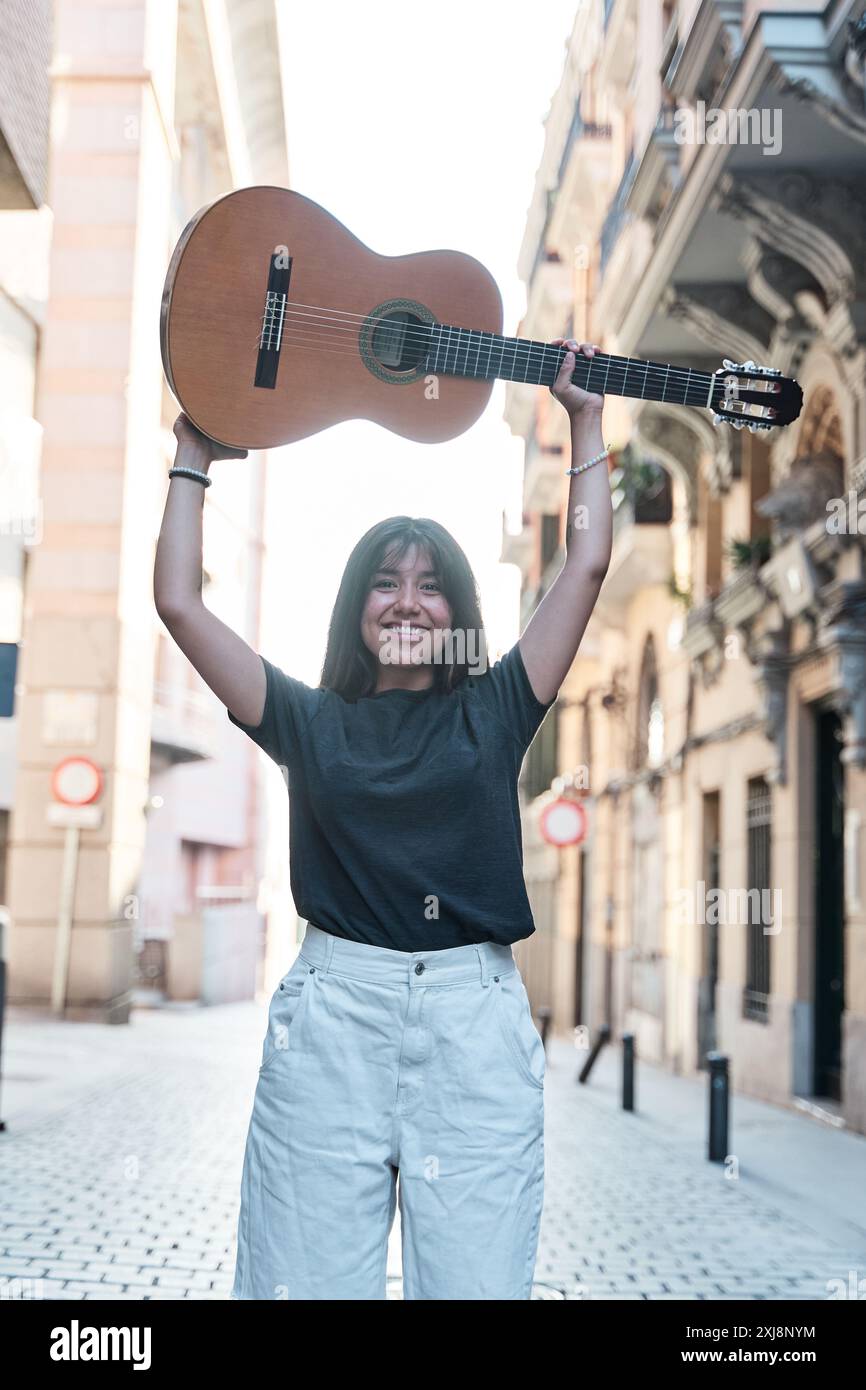 vertical portrait of a young latin woman lifting a classical guitar ...