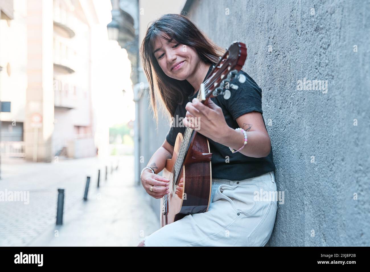 portrait of a young musician playing the guitar in the street leaning ...