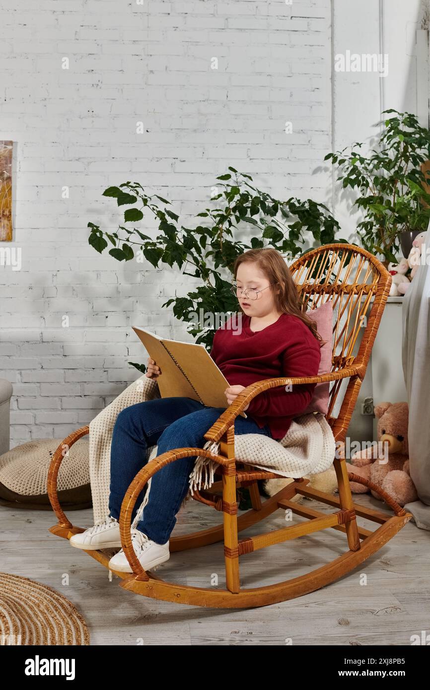 A little girl sits in a wicker rocking chair at home, reading a book ...