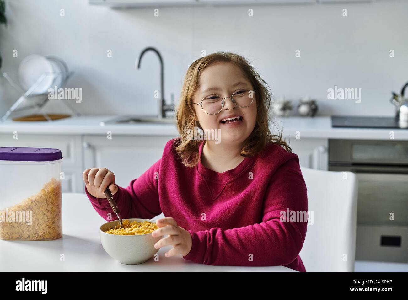 A little girl with Down syndrome smiles while enjoying breakfast at ...
