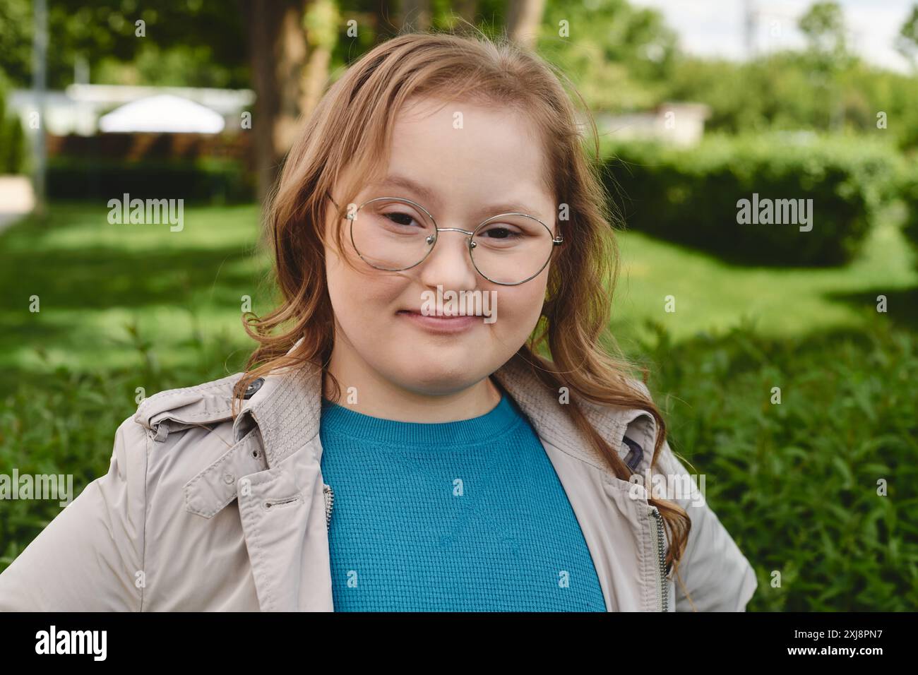 A little girl with Down syndrome smiles brightly while spending time ...