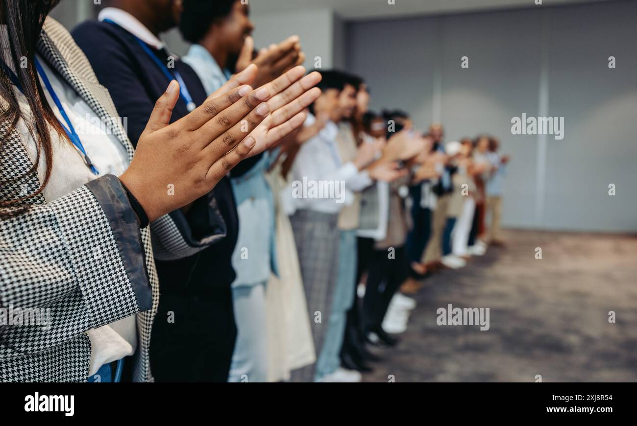 Colleagues clapping hands in celebration during a business conference presentation, highlighting ...
