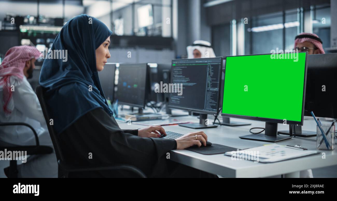 Arab Female Software Developer Working on Desktop Computer with Green Screen Mock Up Display ...