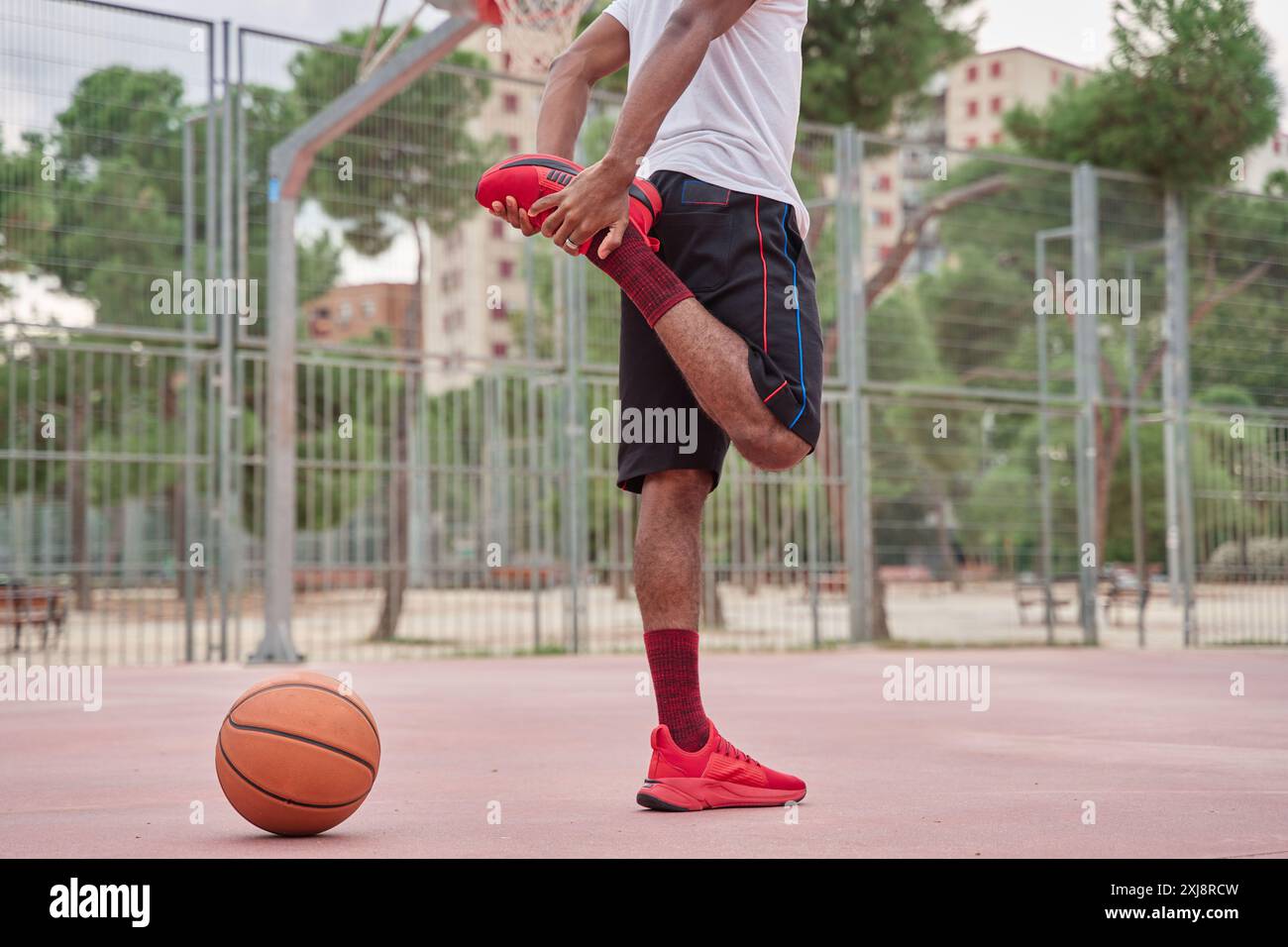 young unrecognizable African-American basketball player stretching his ...