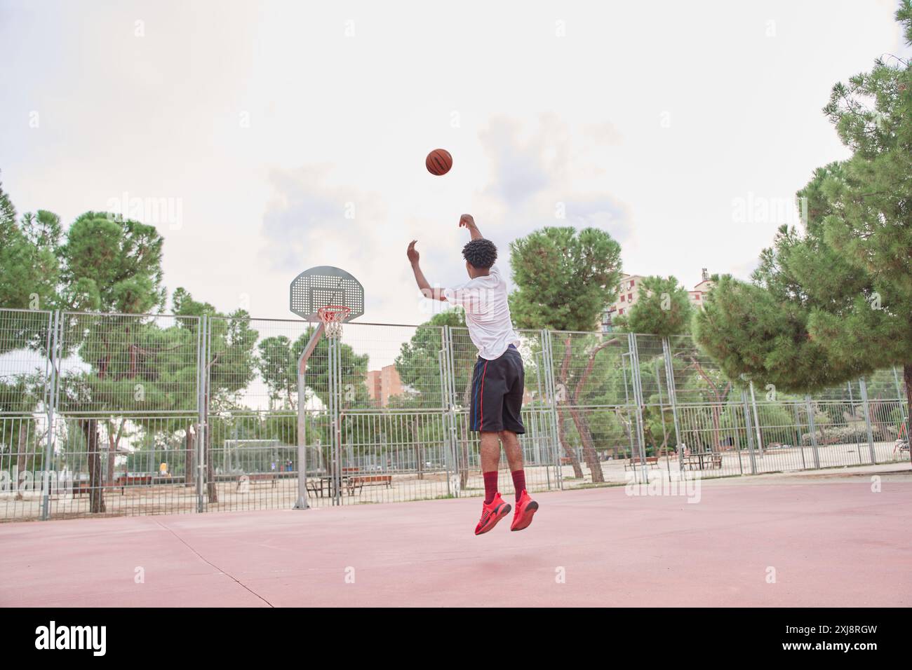 young basketball player shooting a basket while training on a court in ...