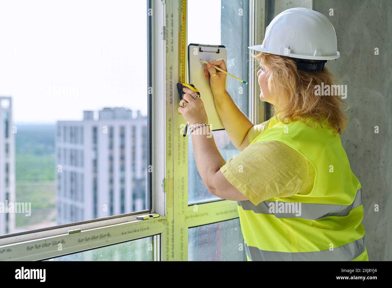 Female window decorator designer measuring window with tape measure ...