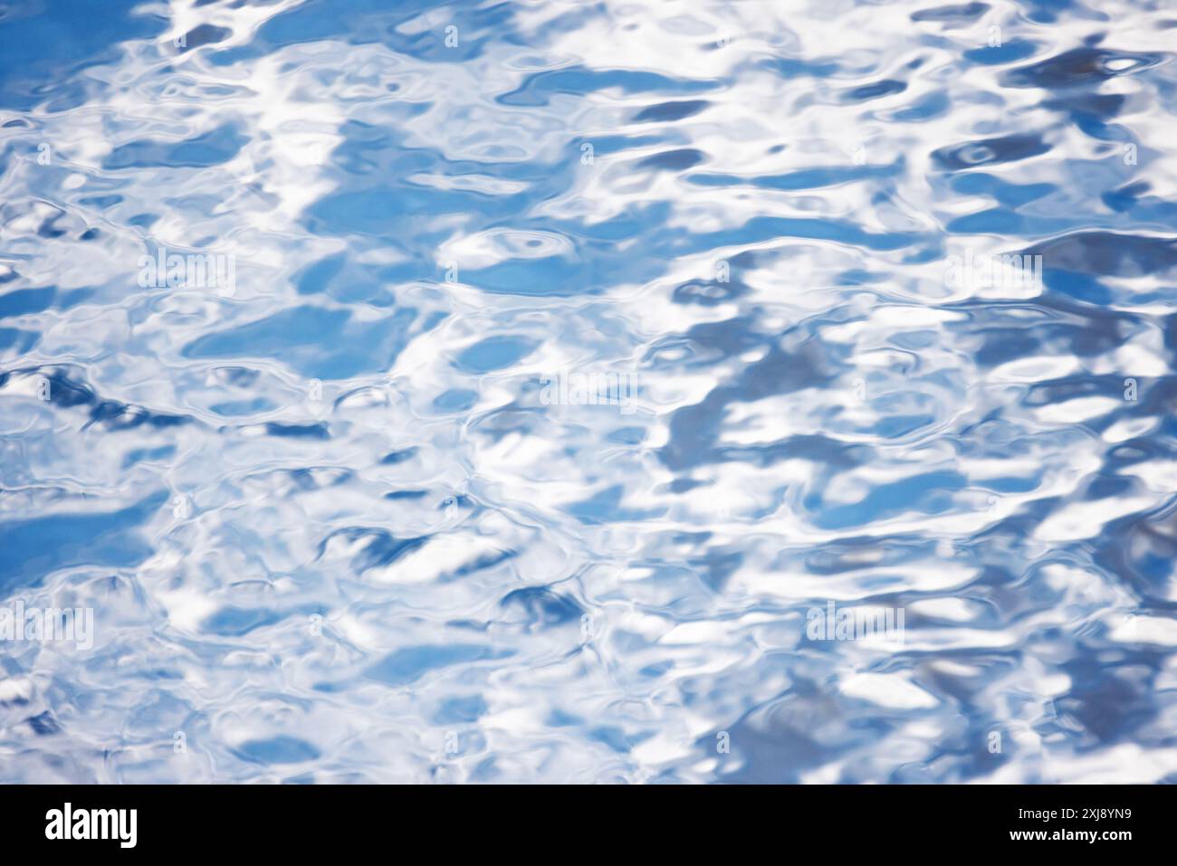 Water surface with wavy reflections of blue sky, abstract natural ...