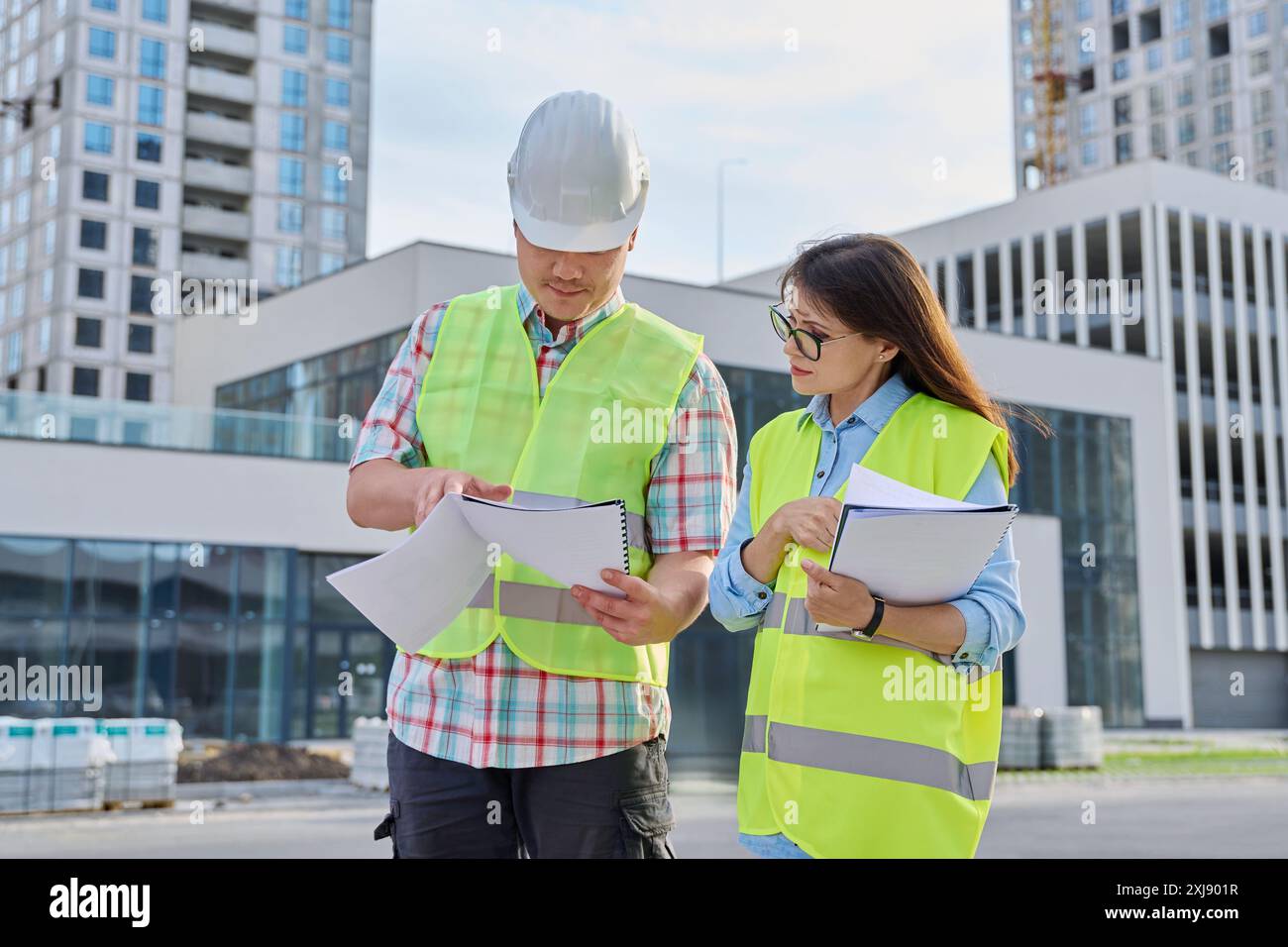 Two industrial construction workers discussing project plan for ...