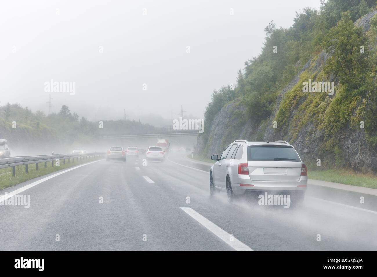 Back tail view of many cars driving fast on wet highway road after rain ...