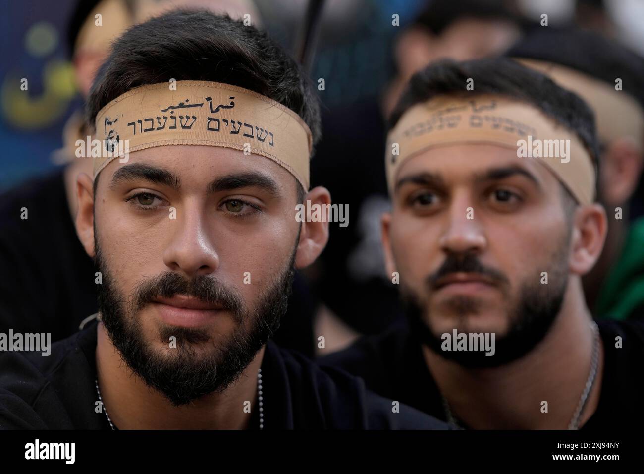Supporters of the Iranian-backed Hezbollah group wear a headband with ...