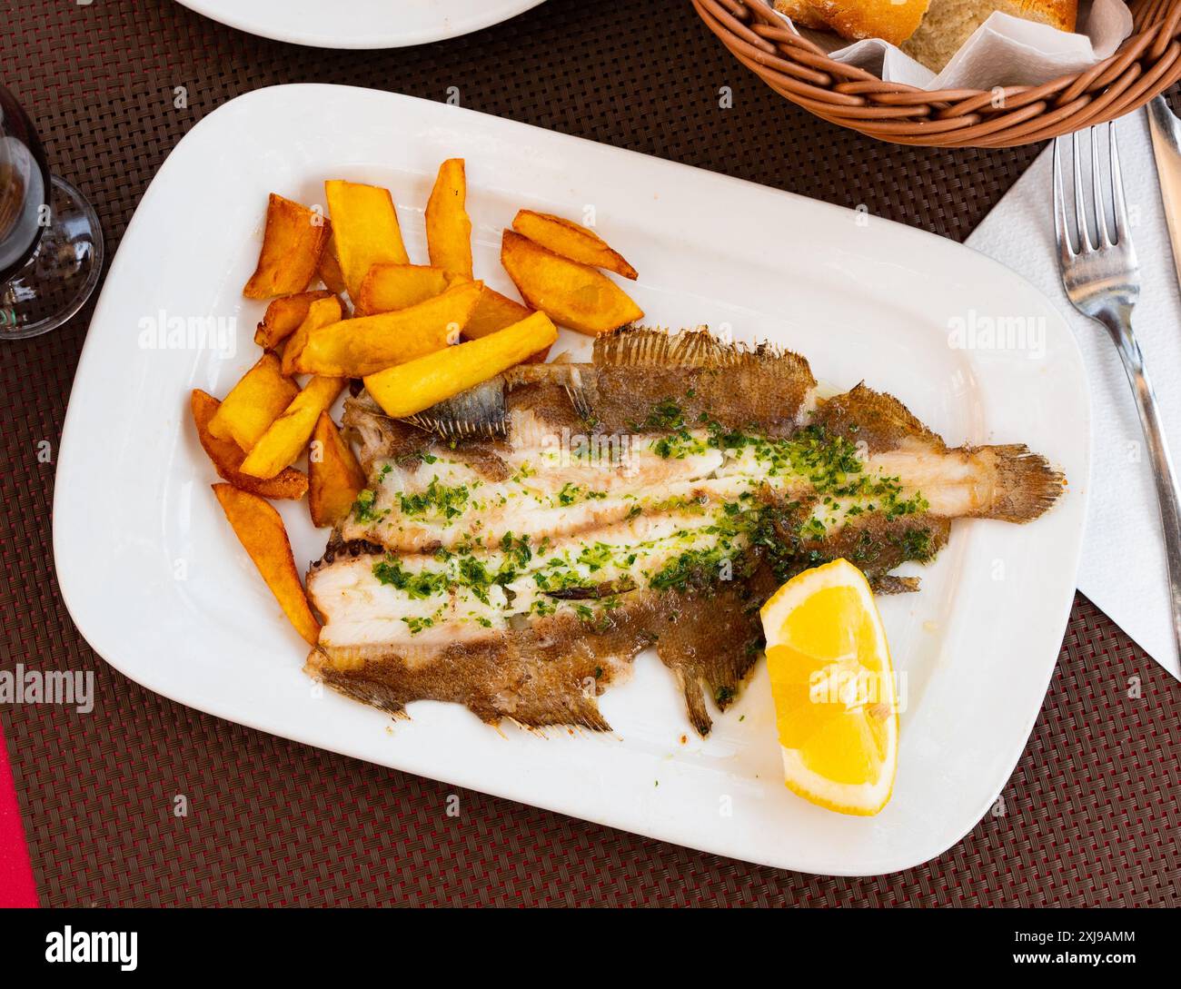 Grilled John Dory fish with herbal oil, fries and lemon Stock Photo - Alamy