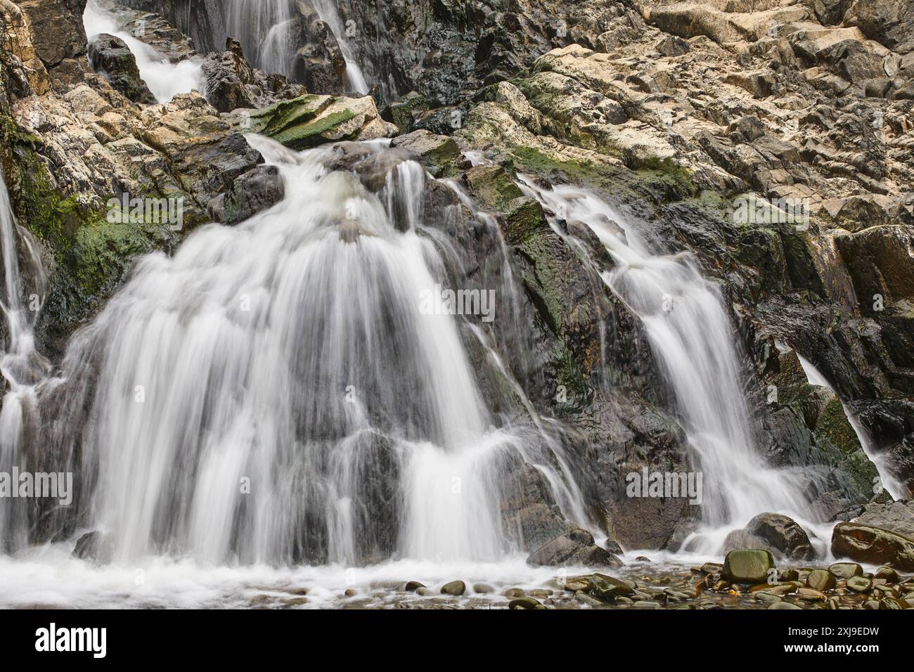 Waterfall pouring down a rocky cliff, with blurred motion, resulting ...