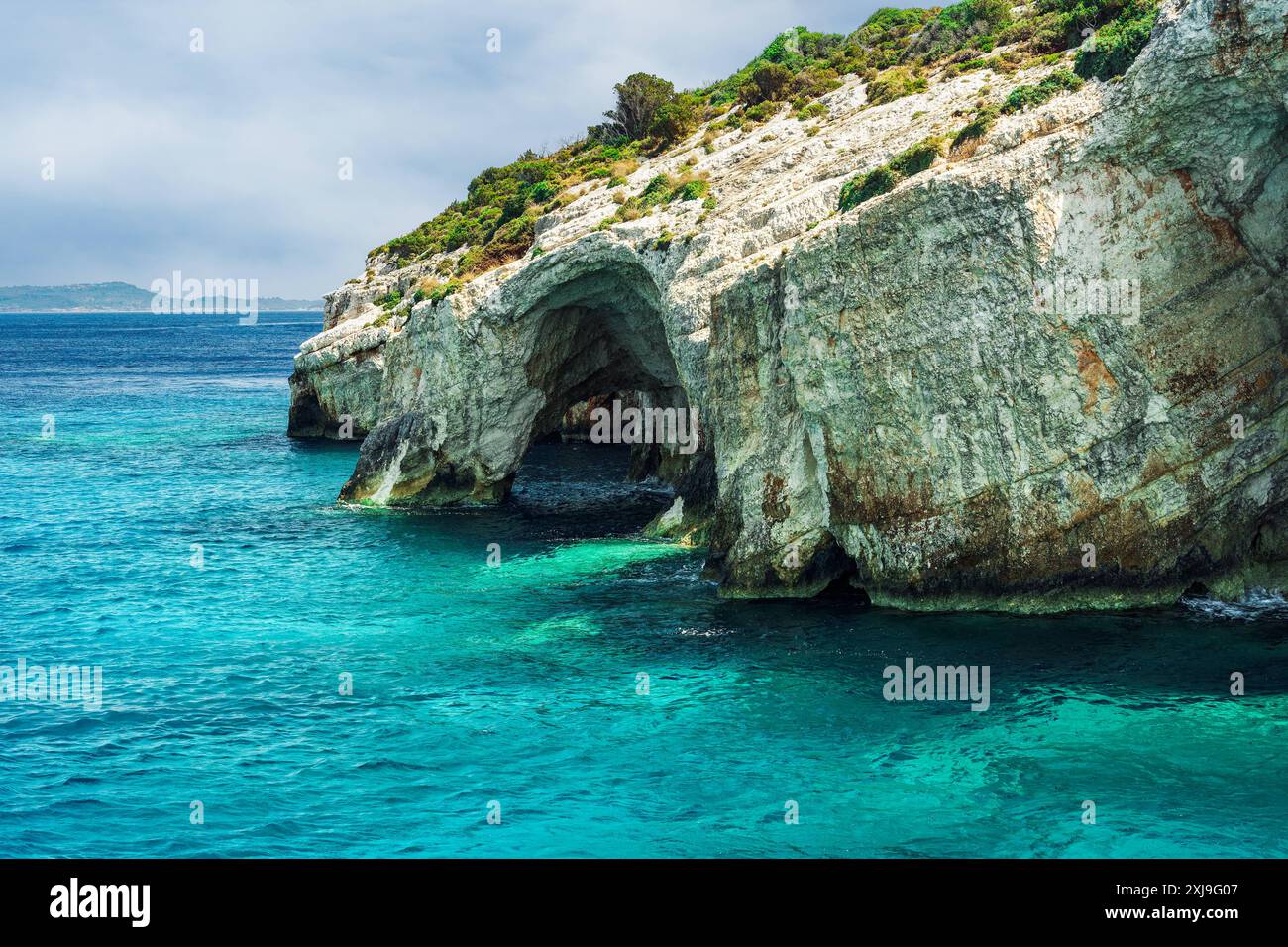 Natural cave formation on a rocky hill with green plantation stretching ...