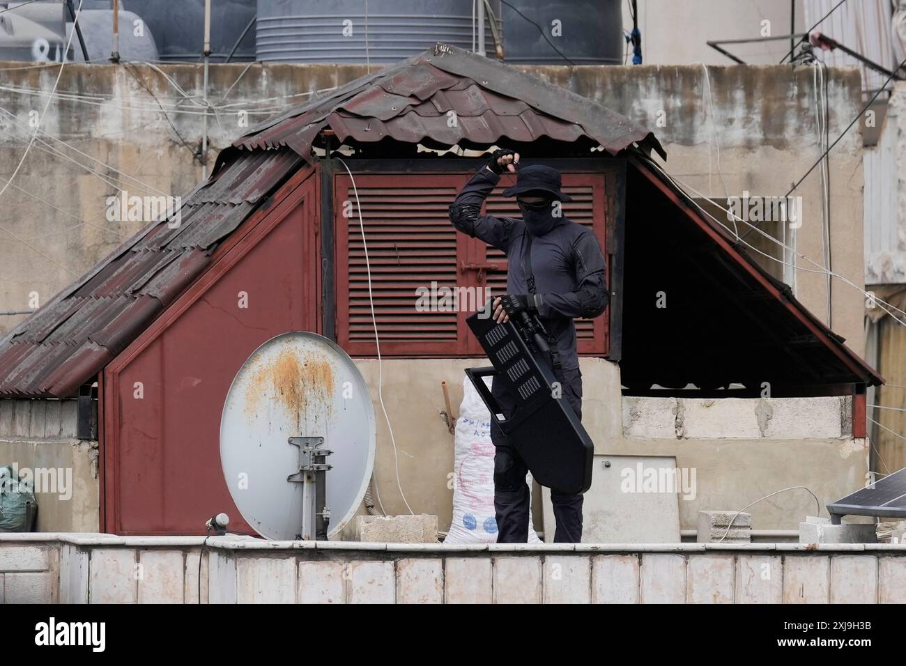 A Hezbollah fighter stands guard on a building roof top as Hezbollah ...