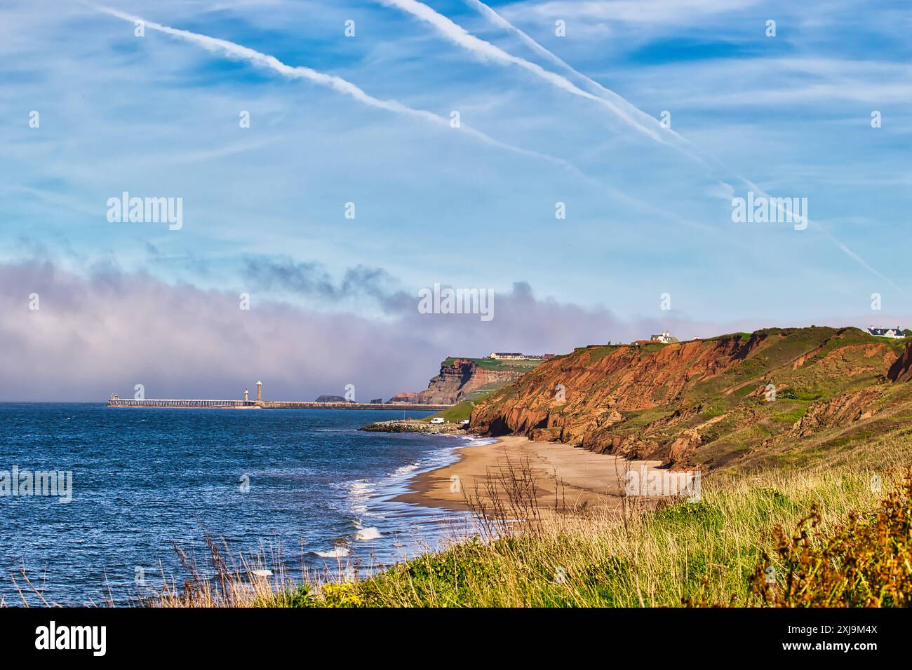 A scenic coastal landscape featuring a sandy beach, cliffs, and a ...