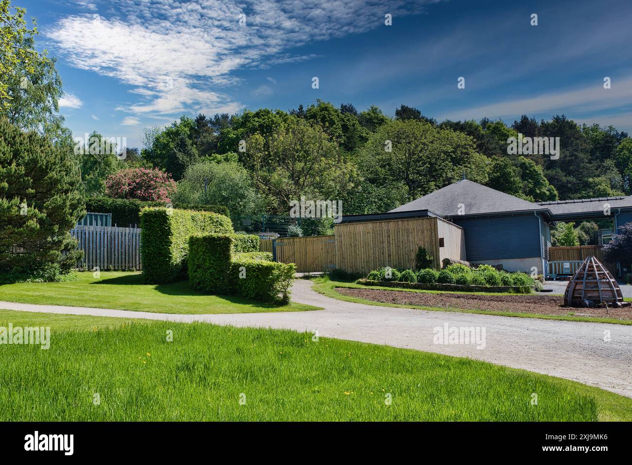A well-maintained garden with a winding gravel path, neatly trimmed ...