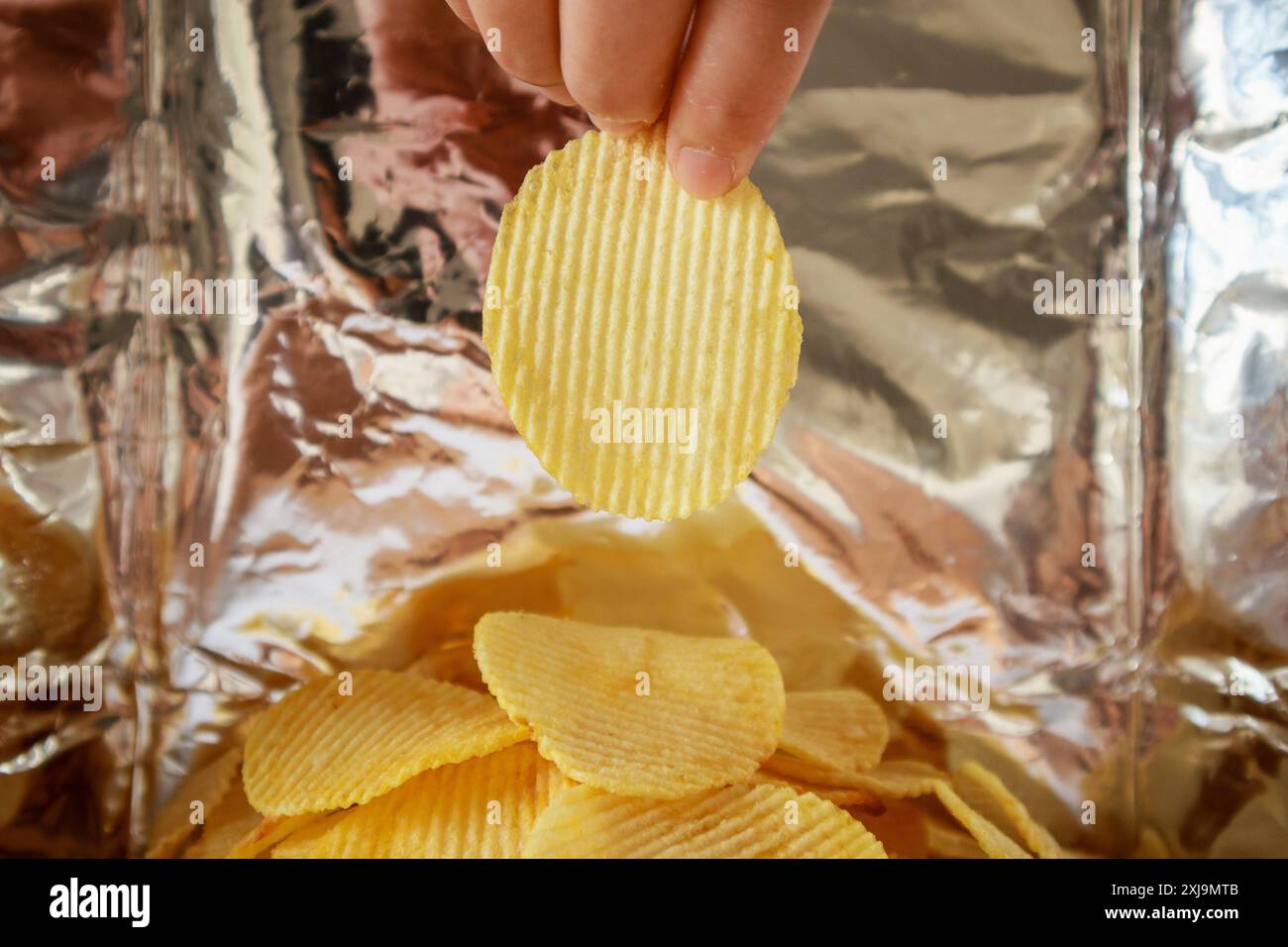 Hand hold potato chips inside snack foil bag Stock Photo - Alamy