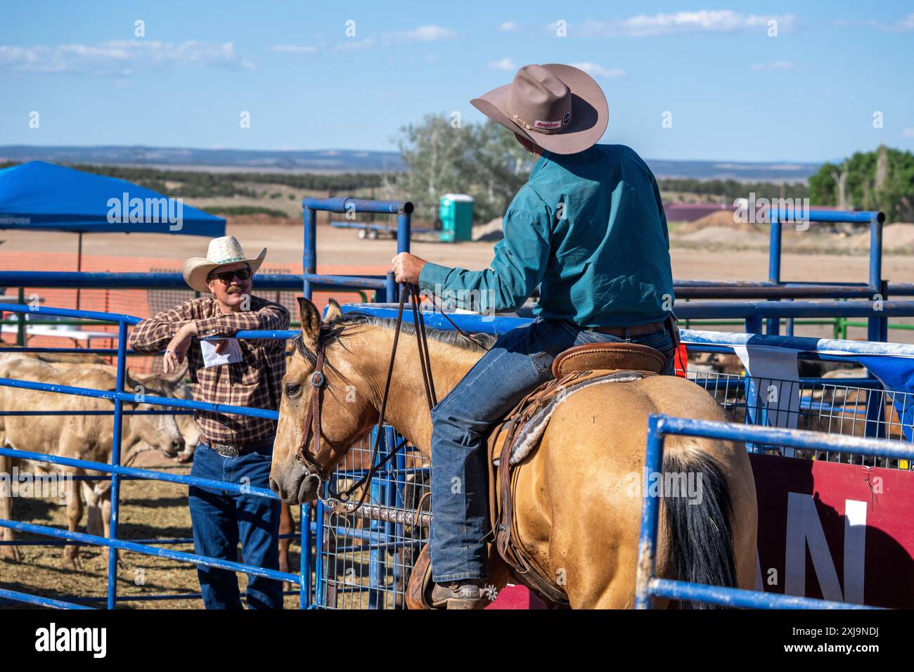 Two rodeo livestock wranglers talking before a rodeo in a small town in ...
