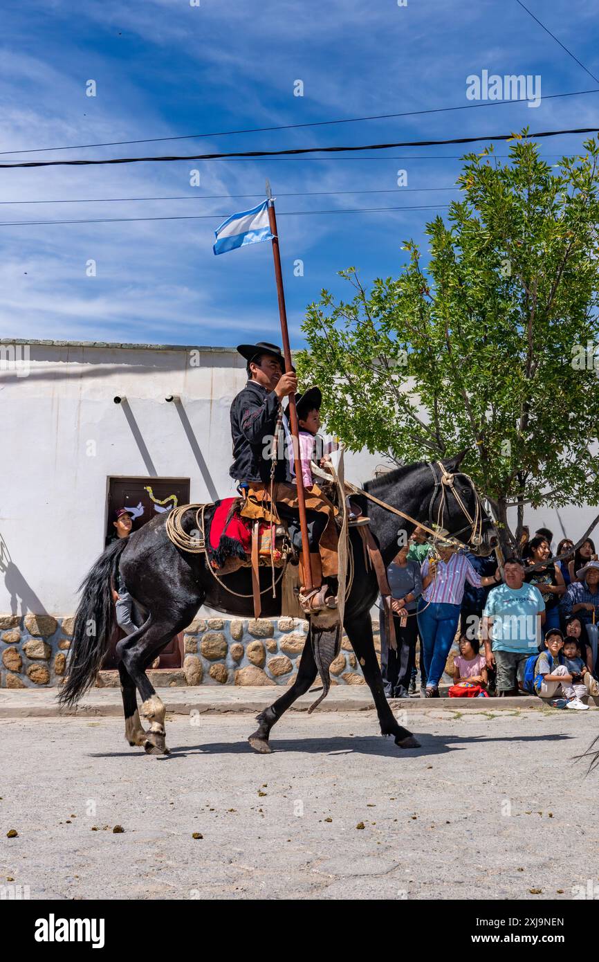 A young gaucho in traditional dress rides with his father in a parade ...