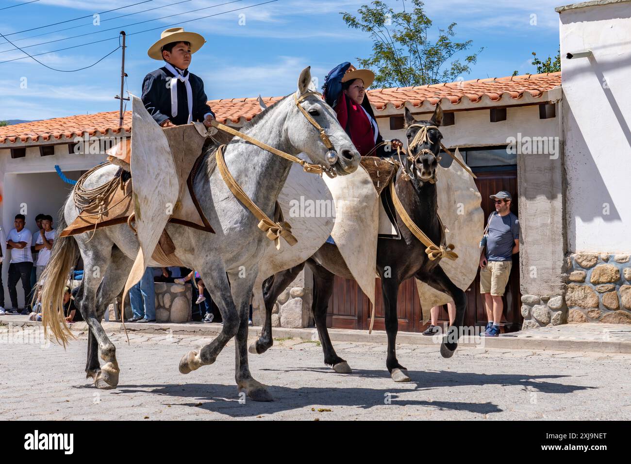 A young gaucho in traditional dress rides with his father in a parade ...